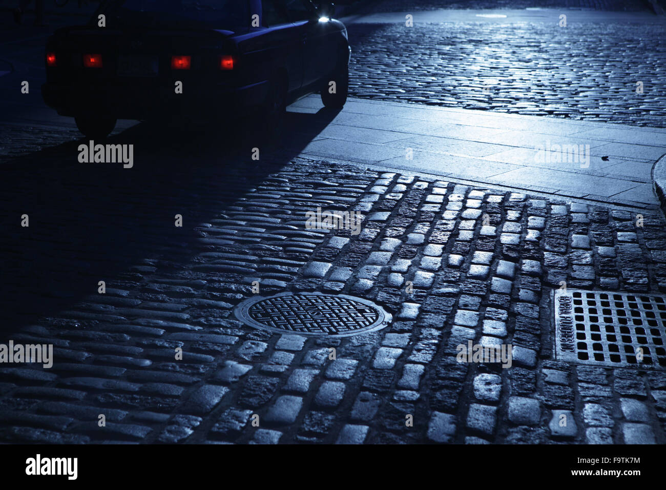 Car driving in blue night shadows on cobblestone road Stock Photo - Alamy