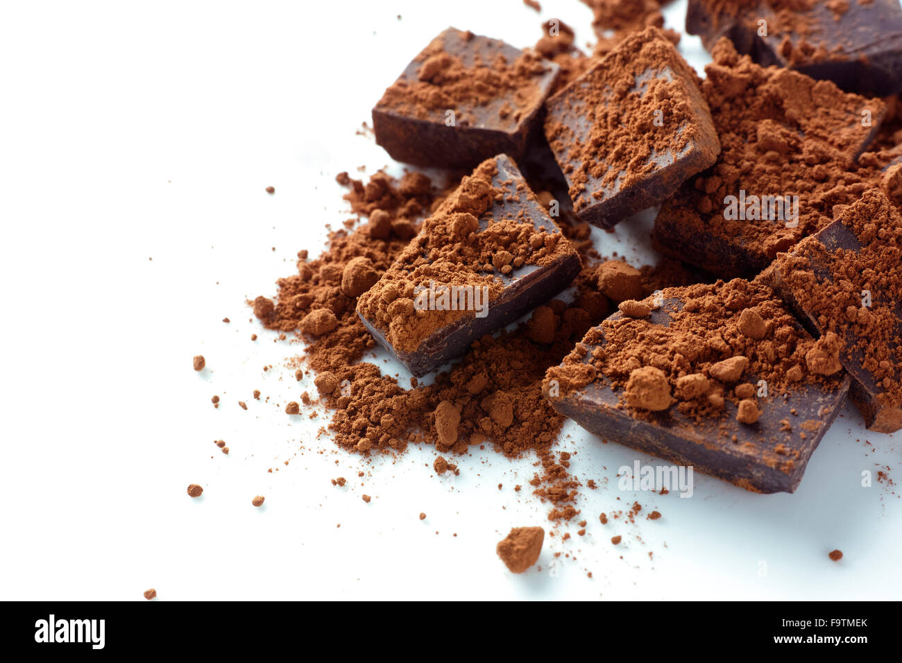 Broken dark chocolate with cocoa powder. White background Stock Photo ...