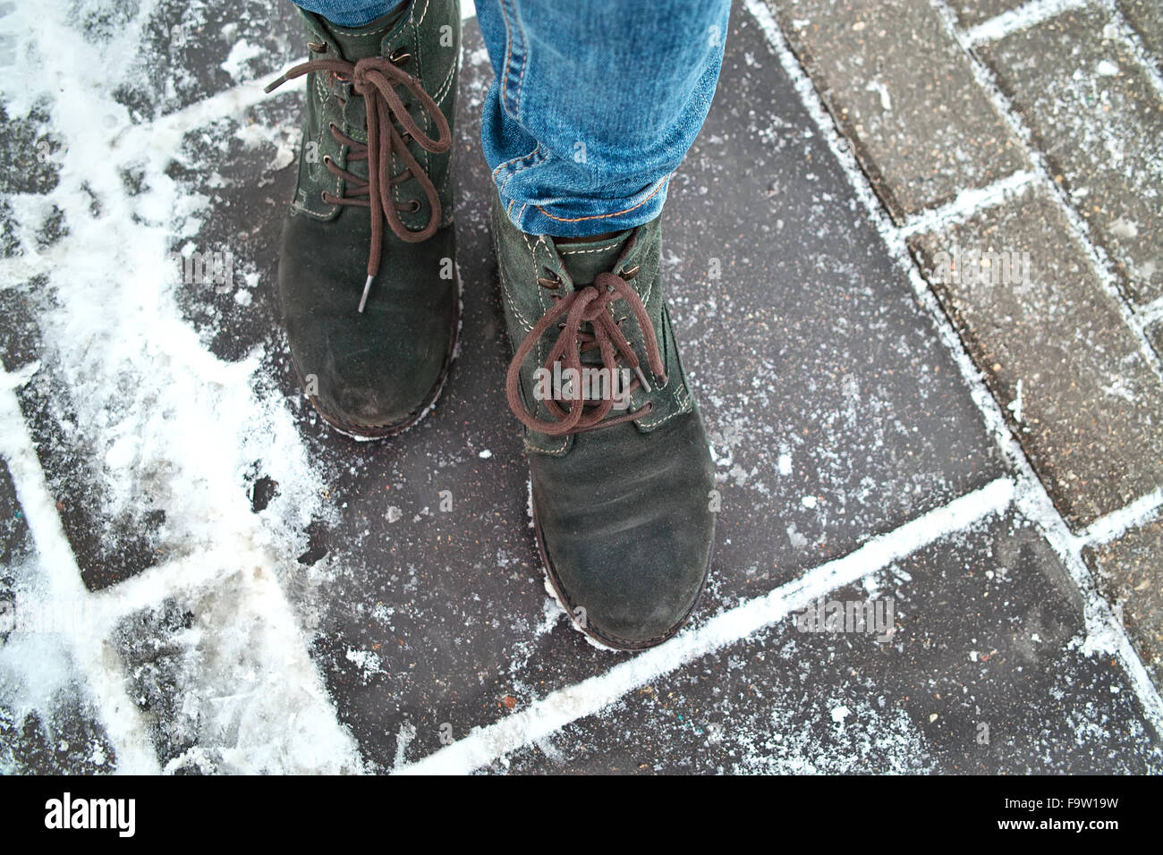 Human feet wearing winter shoes and jeans walking on slippery pavement ...