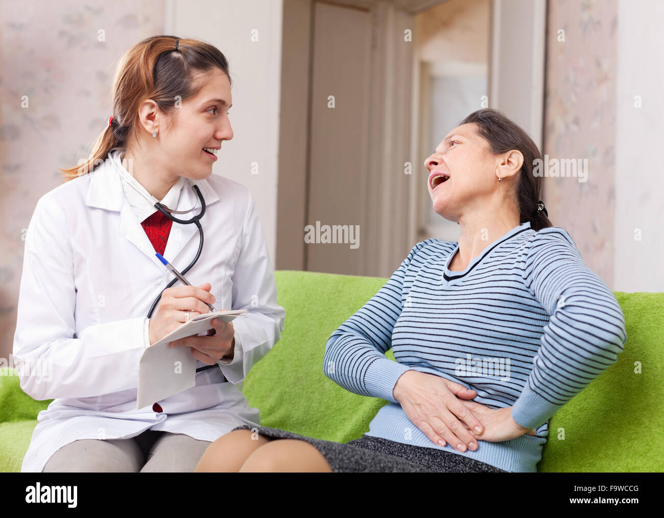 sick woman complaining to doctor about stitch in side at home Stock ...