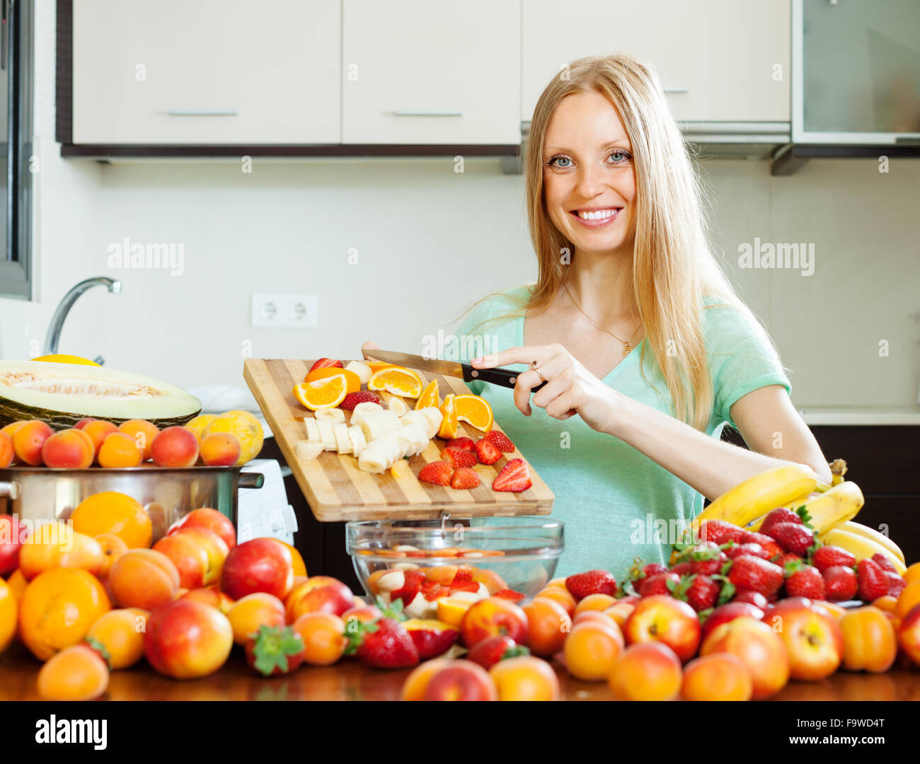 Positive long-haired woman cooking fruit salad Stock Photo - Alamy