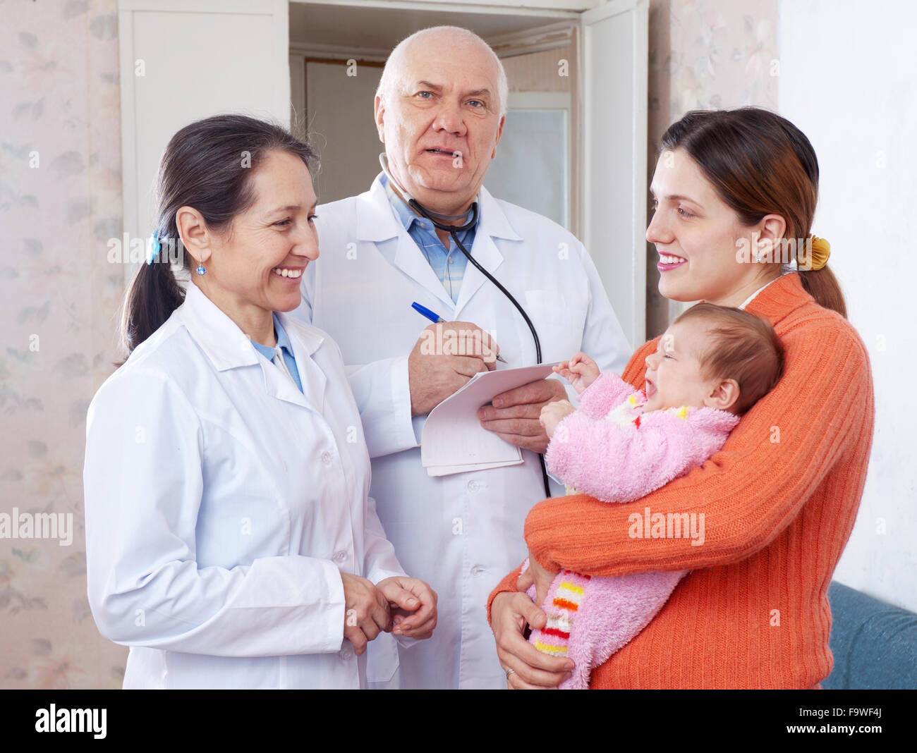 pediatrician doctors examining little baby in the arms of mother Stock ...