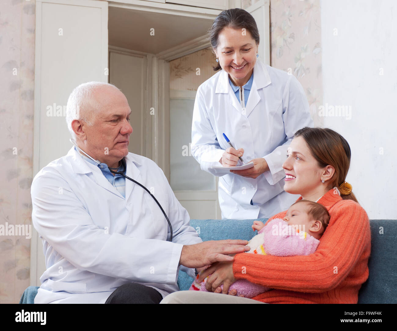 pediatrician doctor examining three months baby on mother's arms ...