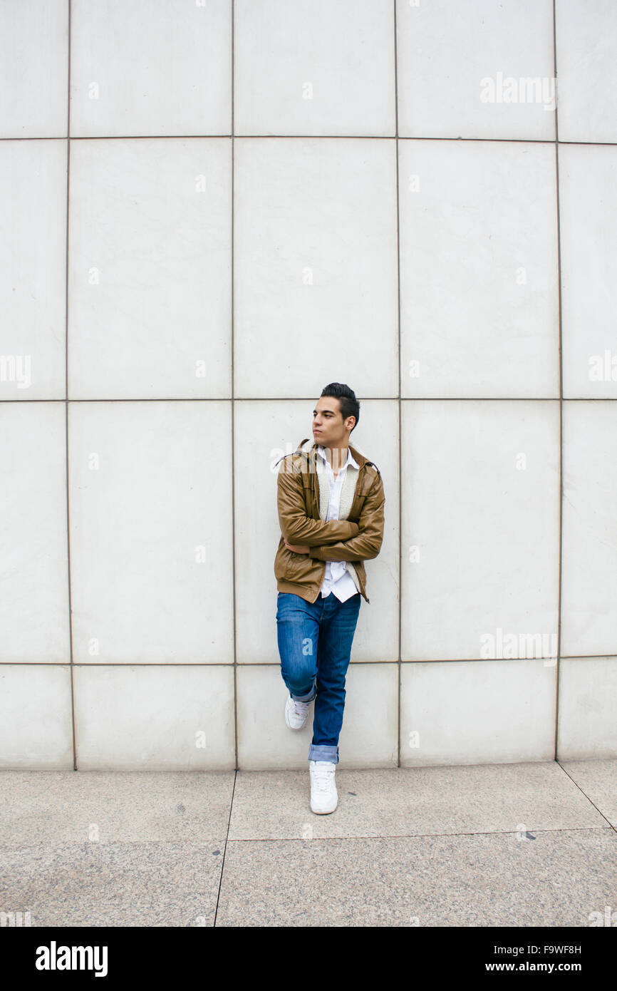 Teenager leaning against a wall looking around Stock Photo - Alamy