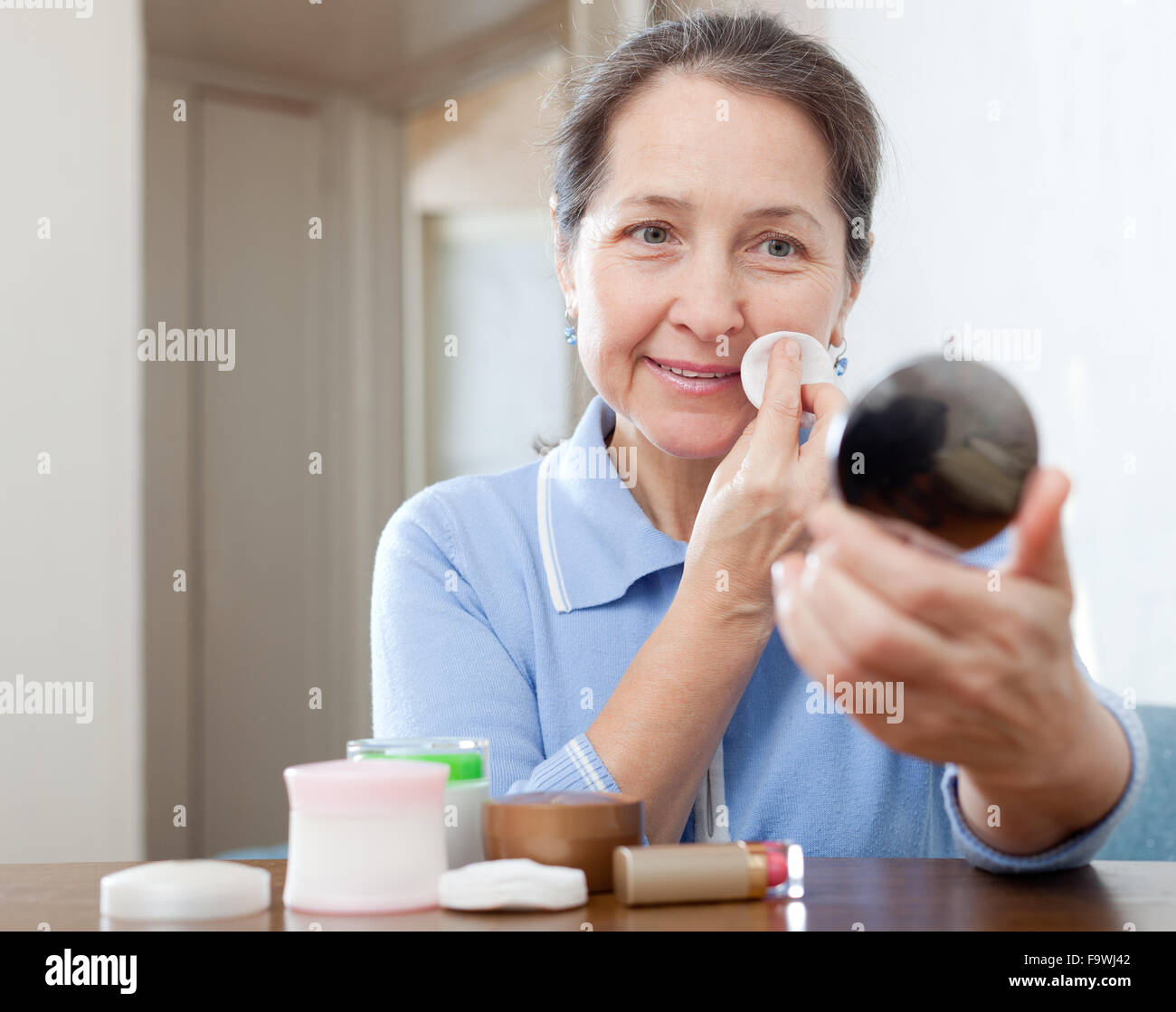 Mature woman cleans the make-up from face Stock Photo - Alamy