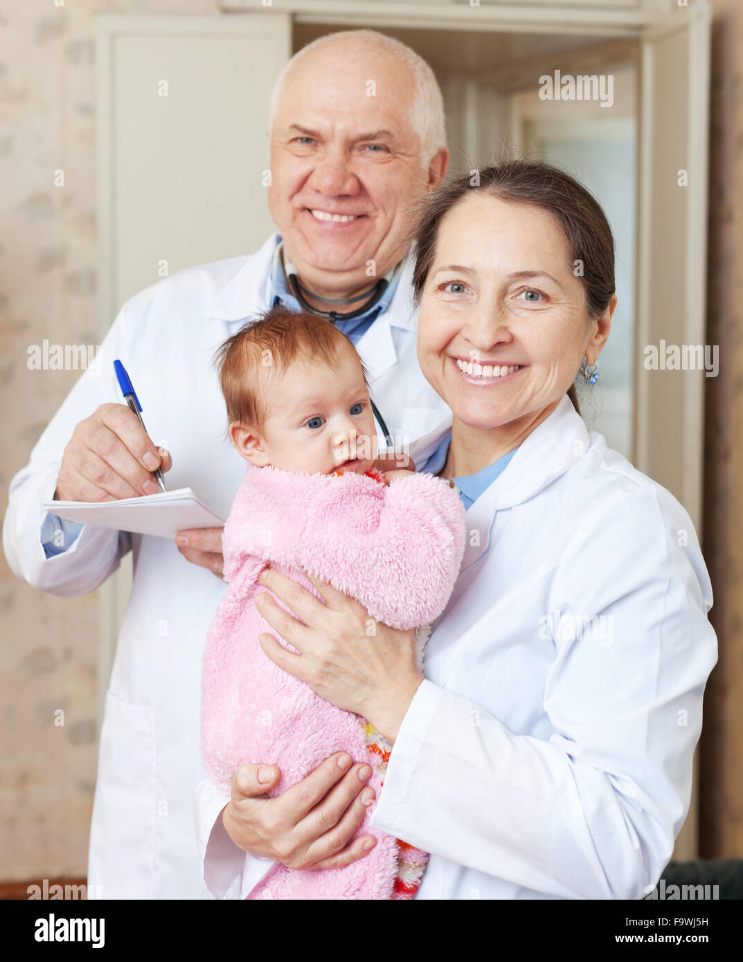 Two pediatrician doctors with baby in interior Stock Photo - Alamy