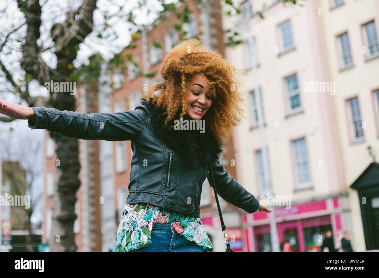 Ireland, Dublin, smiling woman with afro balancing Stock Photo - Alamy