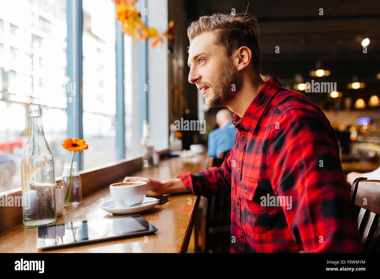 Man in a coffee shop looking out of window Stock Photo - Alamy