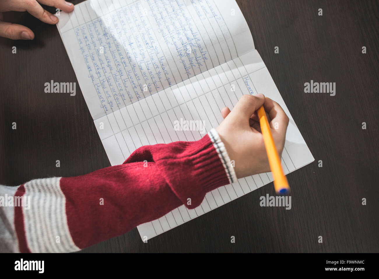Hand of a boy writing in a notebook Stock Photo - Alamy