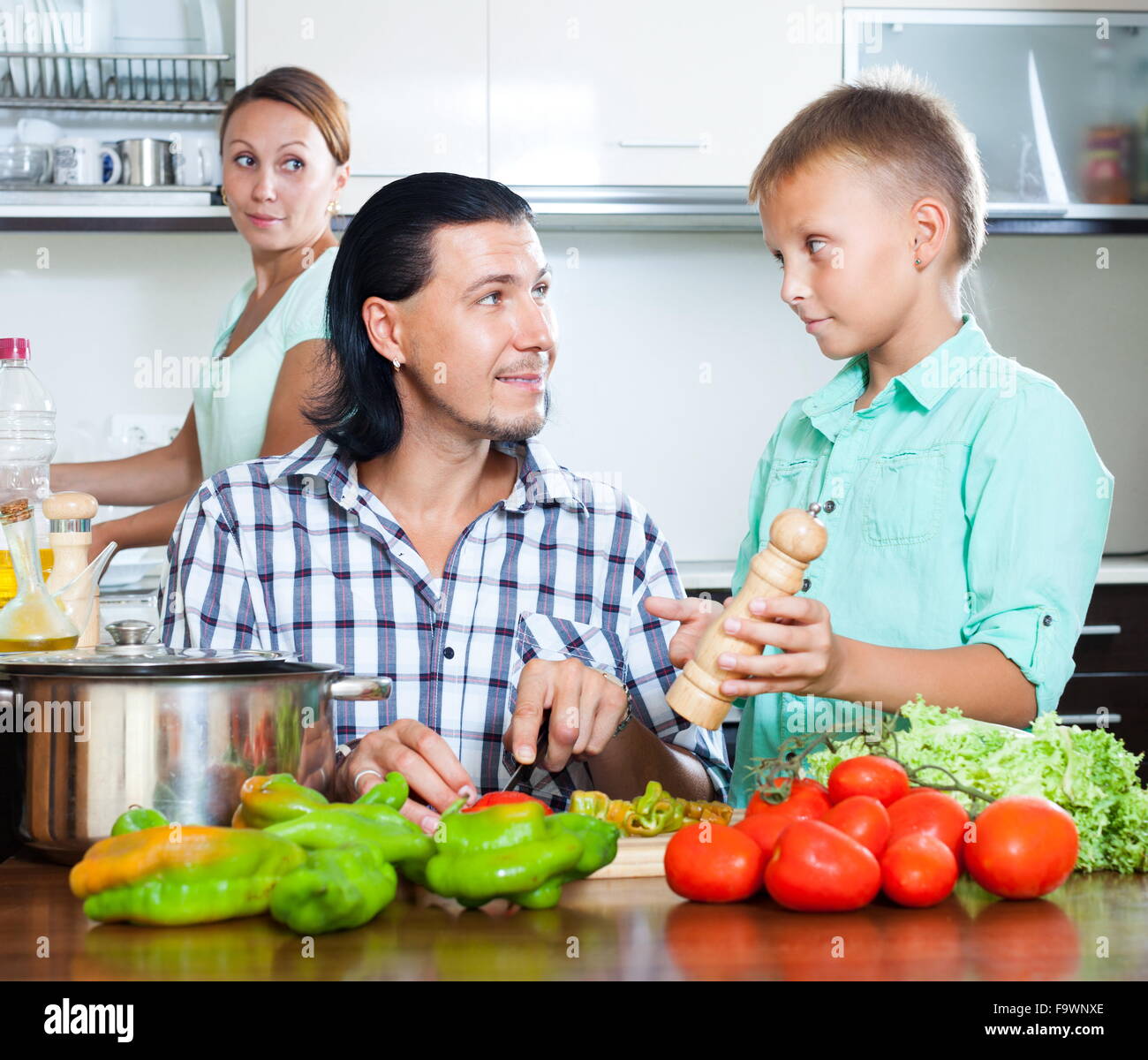 Happy family of three with vegetables in kitchen Stock Photo - Alamy