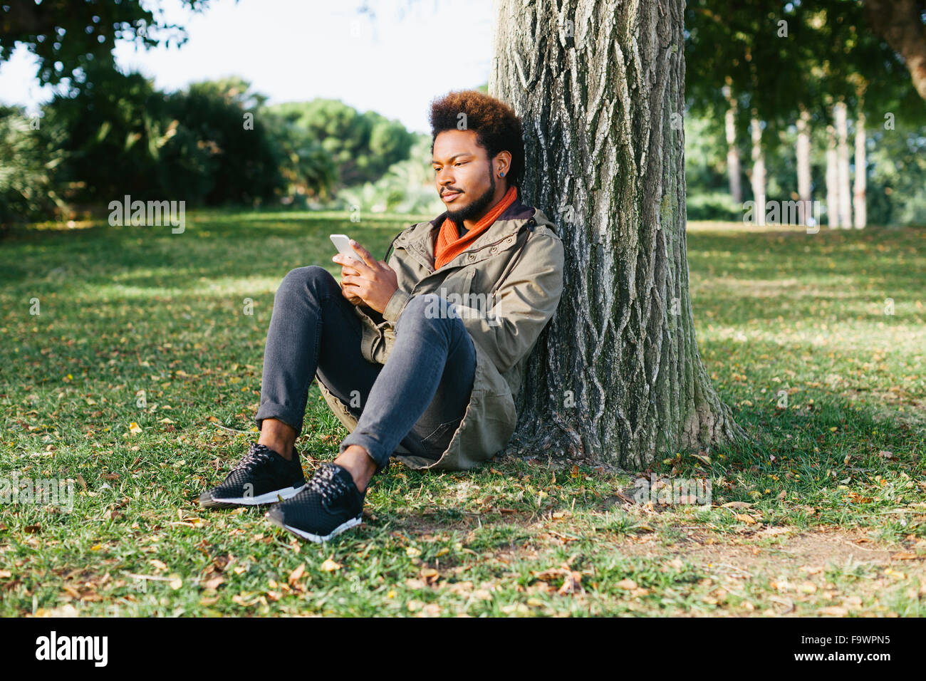 Man sitting against tree trunk hi-res stock photography and images - Alamy