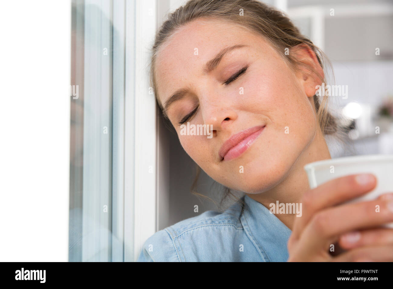 Young woman sitting at the window, drinking coffee Stock Photo - Alamy