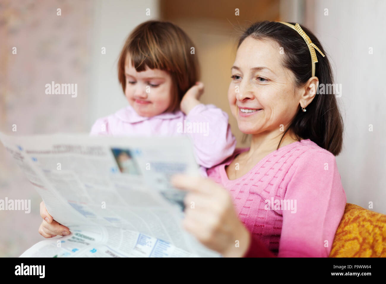 Positive grandmother and child reading newspaper at home Stock Photo - Alamy