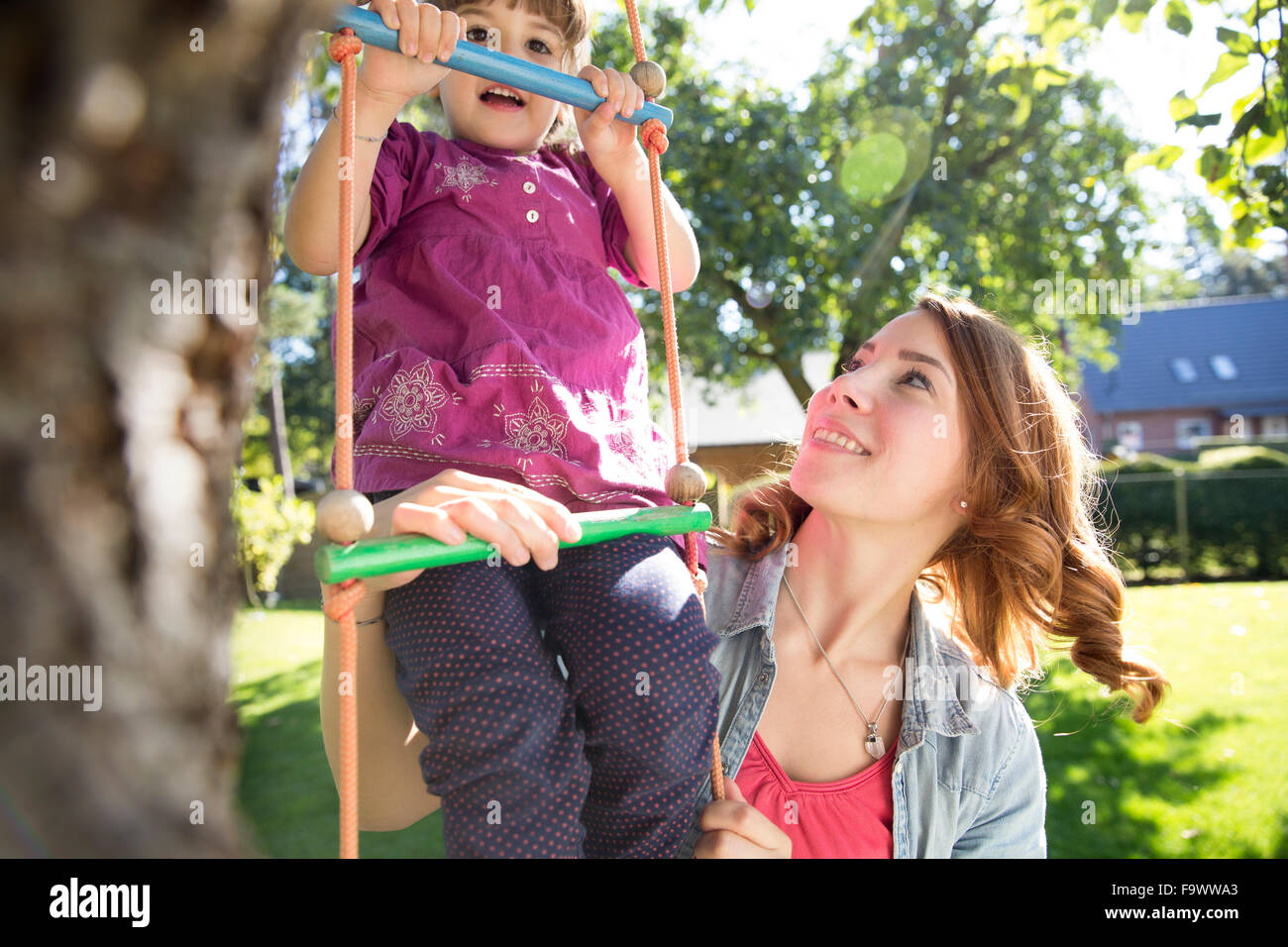 Mother watching daughter on rope ladder in garden Stock Photo - Alamy