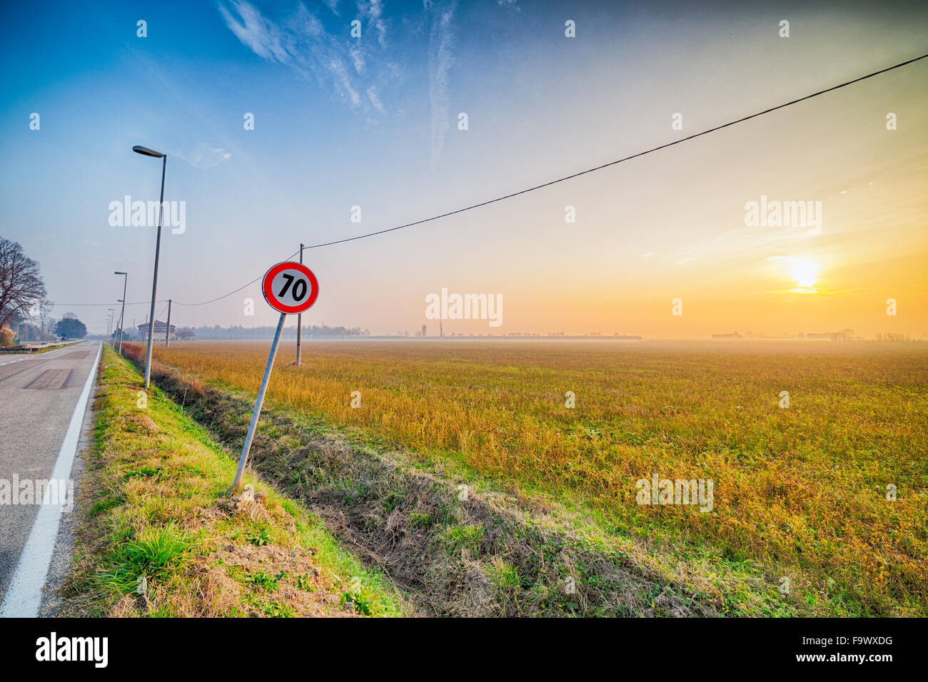 sunset on country road with speed limit signal Stock Photo - Alamy
