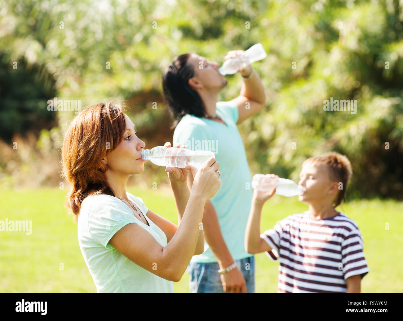 parents with teenager boy drinking clean water from plastic bottles ...