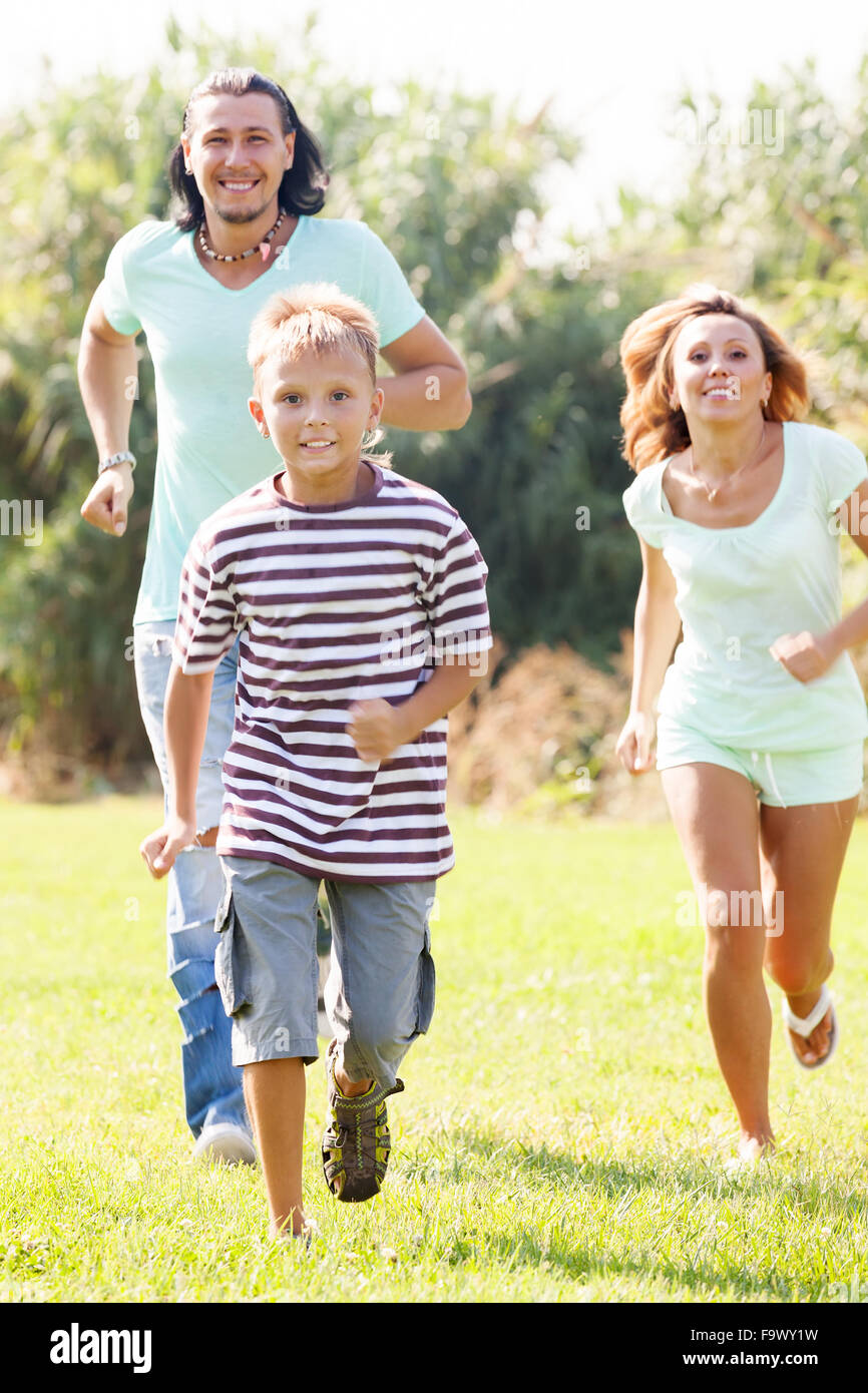 Sporty family of three running on grass at park Stock Photo - Alamy