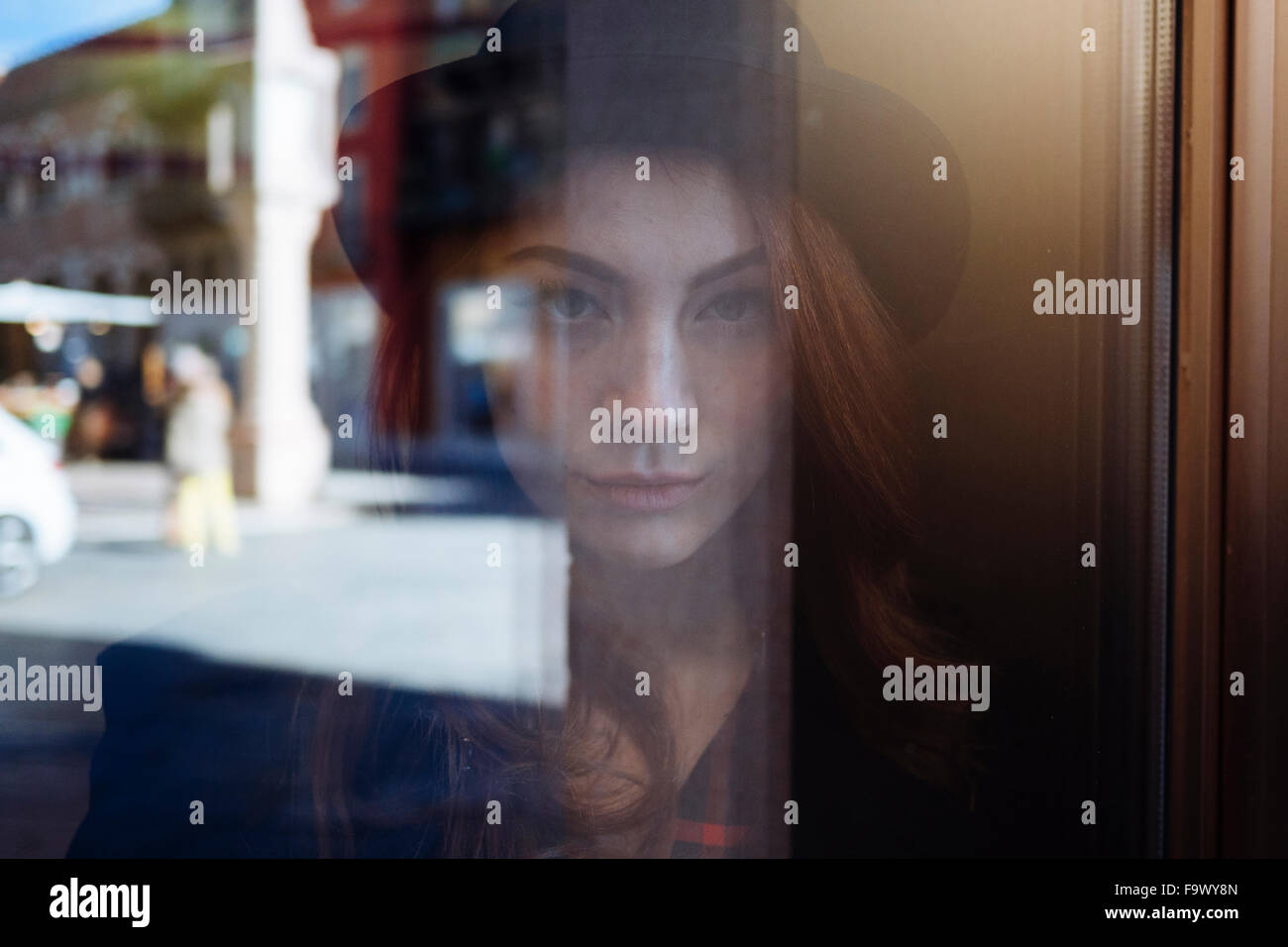 Portrait of young woman behind window pane Stock Photo - Alamy