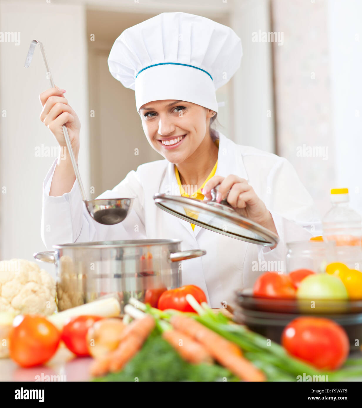 Happy young cook tests vegetarian food with ladle at commercial kitchen ...