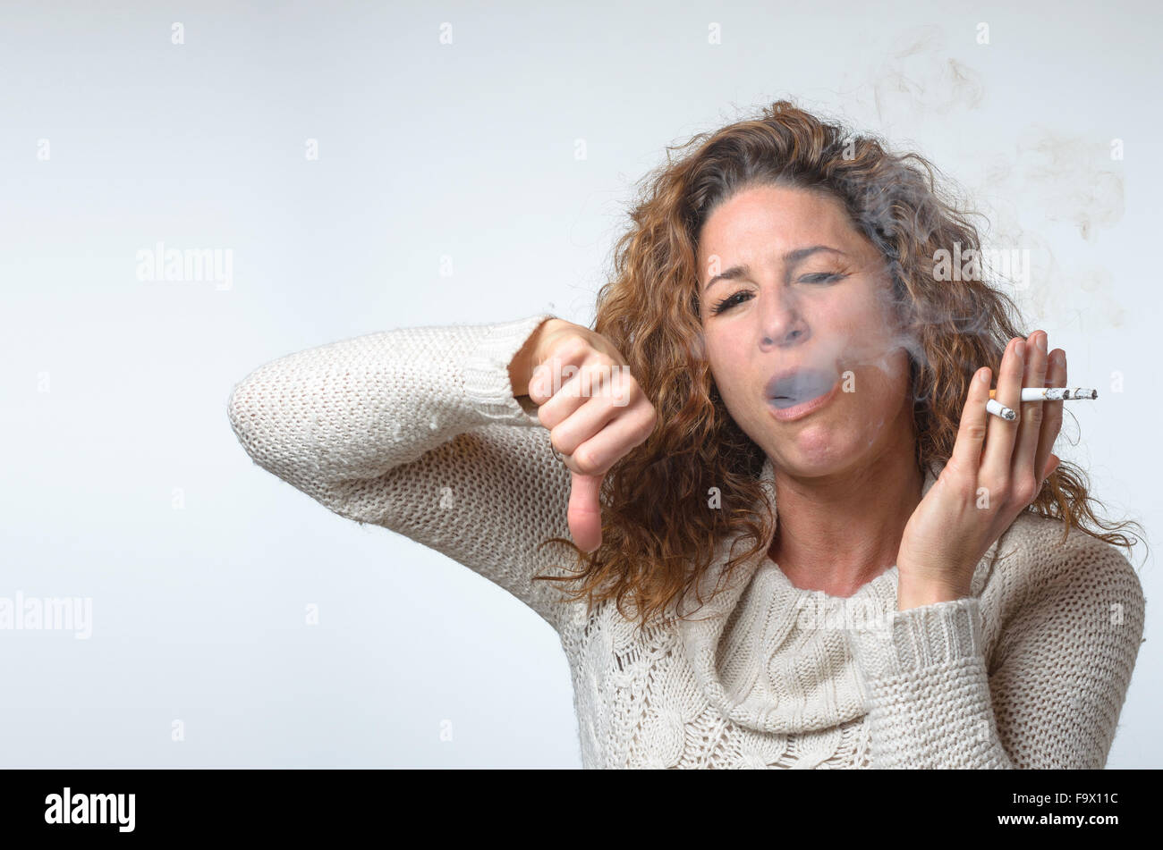 Attractive young woman smoking three cigarettes inhaling with a look of ...