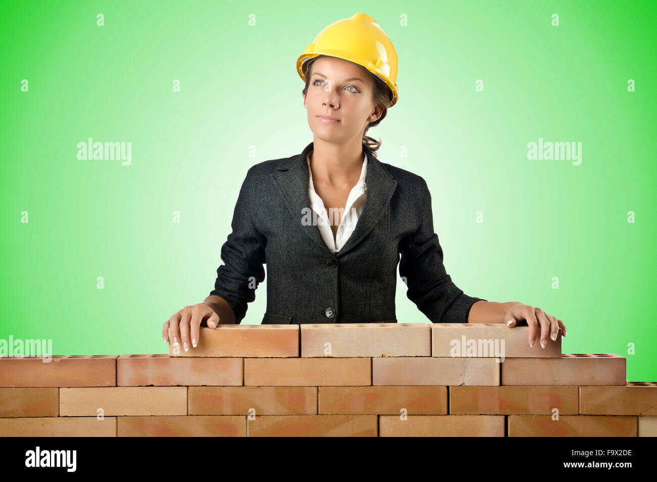 Young female builder near brick wall Stock Photo - Alamy