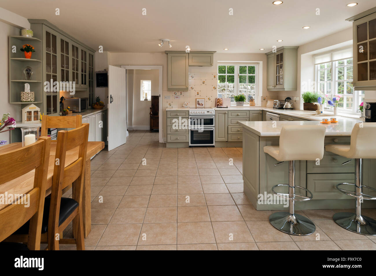 Large paint finshed fitted kitchen with dining table Stock Photo - Alamy