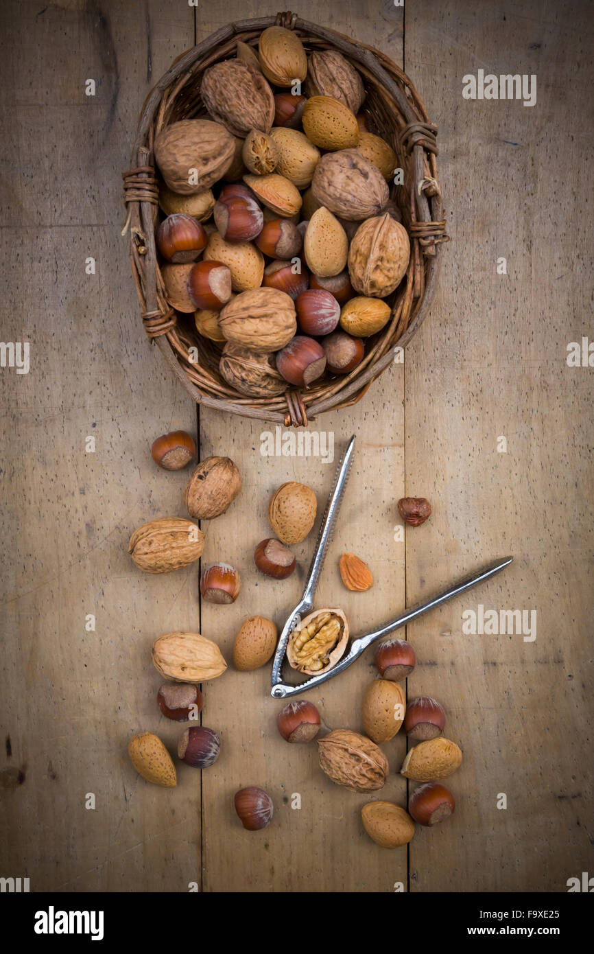 Wickerbasket, walnuts, almonds, hazelnuts and nutcracker on wood Stock ...