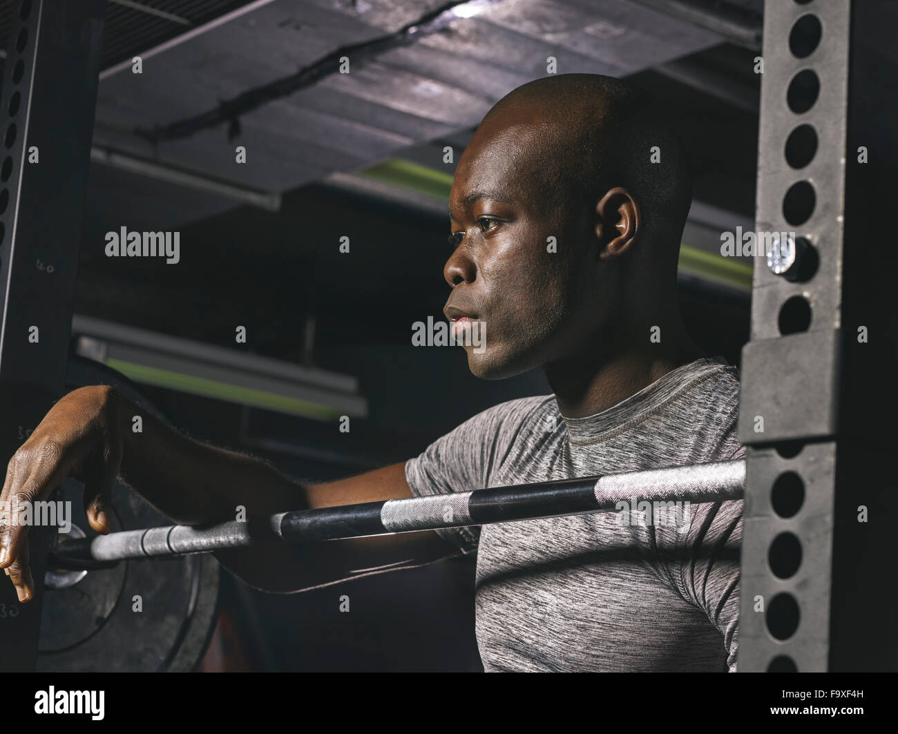 Physical athlete resting on barbell in gym Stock Photo - Alamy