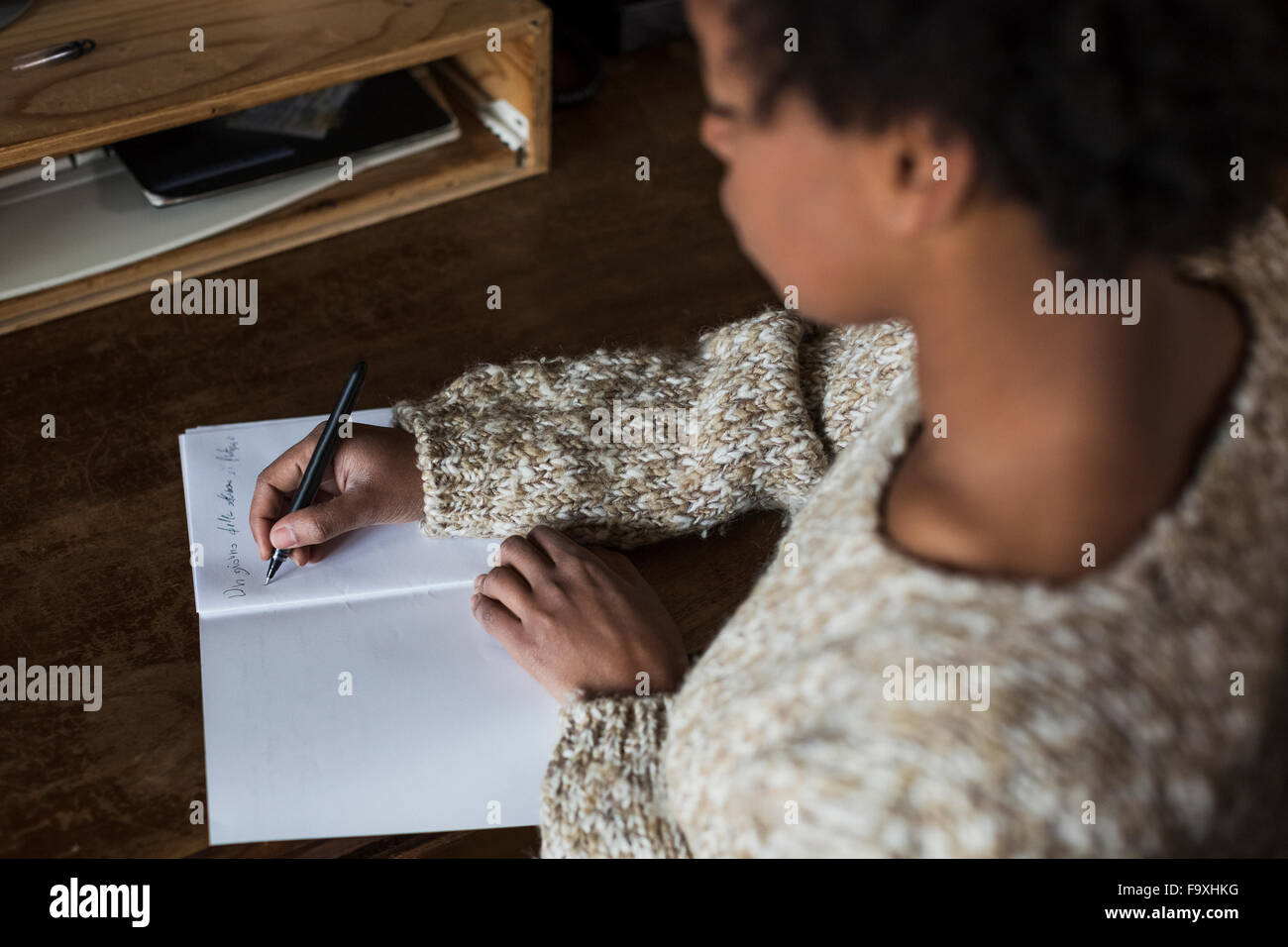 Young woman at desk writing in notebook Stock Photo - Alamy