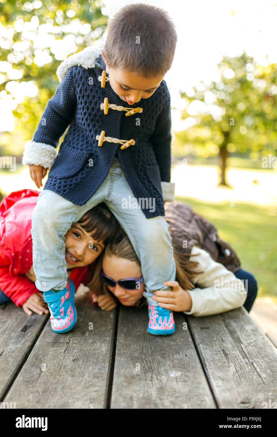 Three children playing together in a park Stock Photo - Alamy