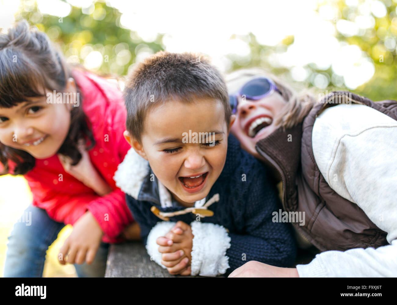 Three laughing children playing together in a park Stock Photo - Alamy