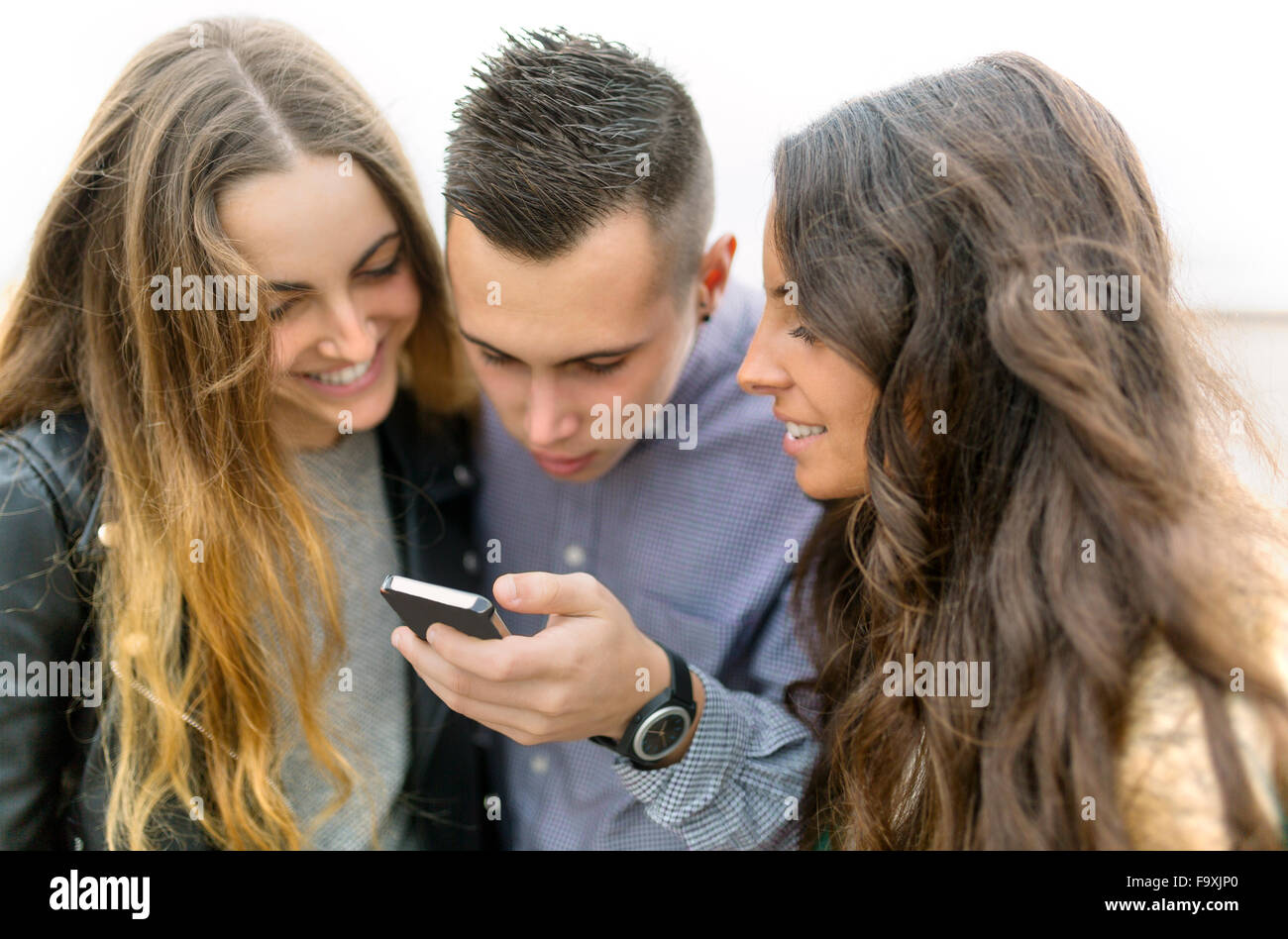 Three friends looking at cell phone together Stock Photo - Alamy
