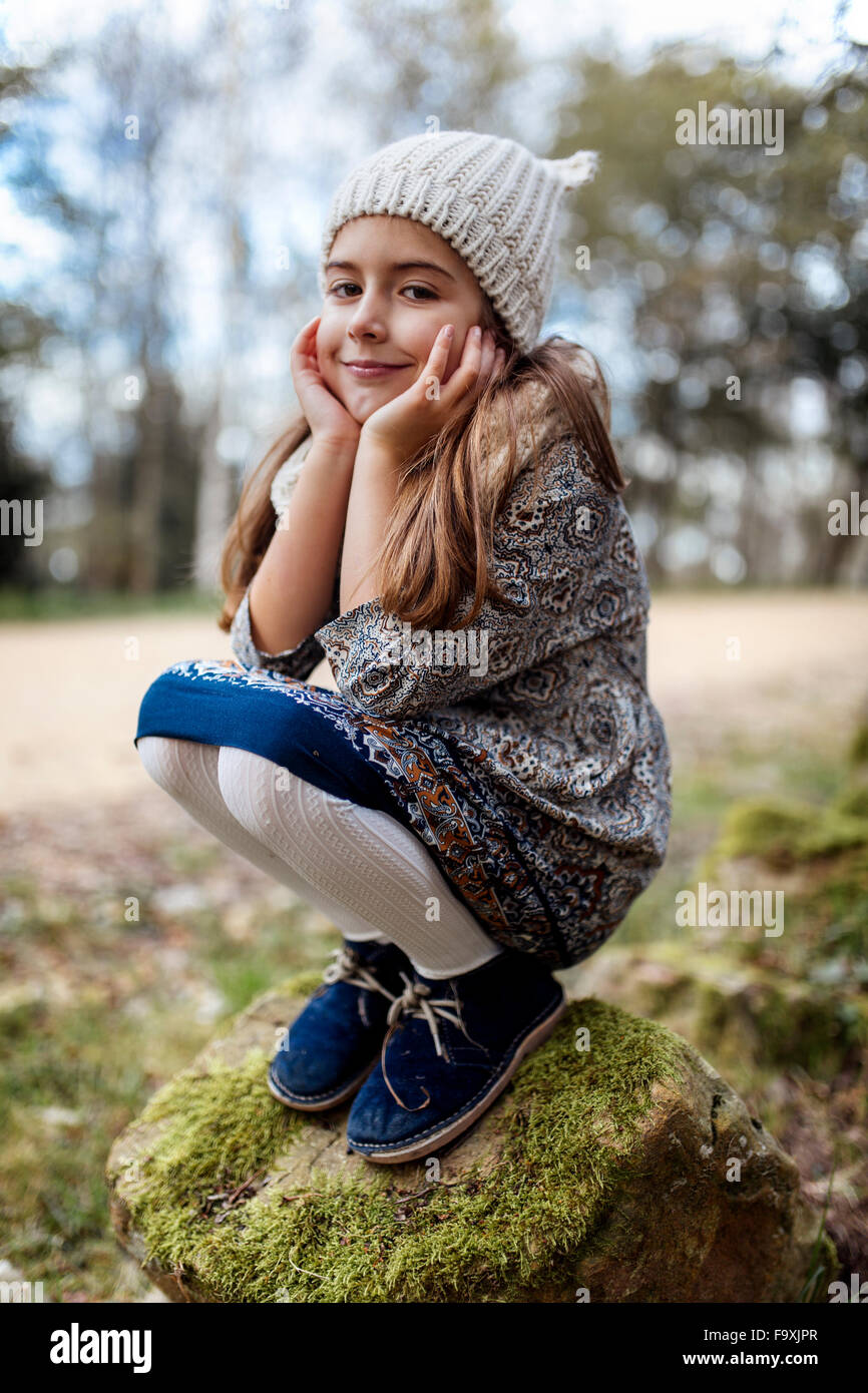 Portrait of smiling girl crouching on boulder Stock Photo - Alamy