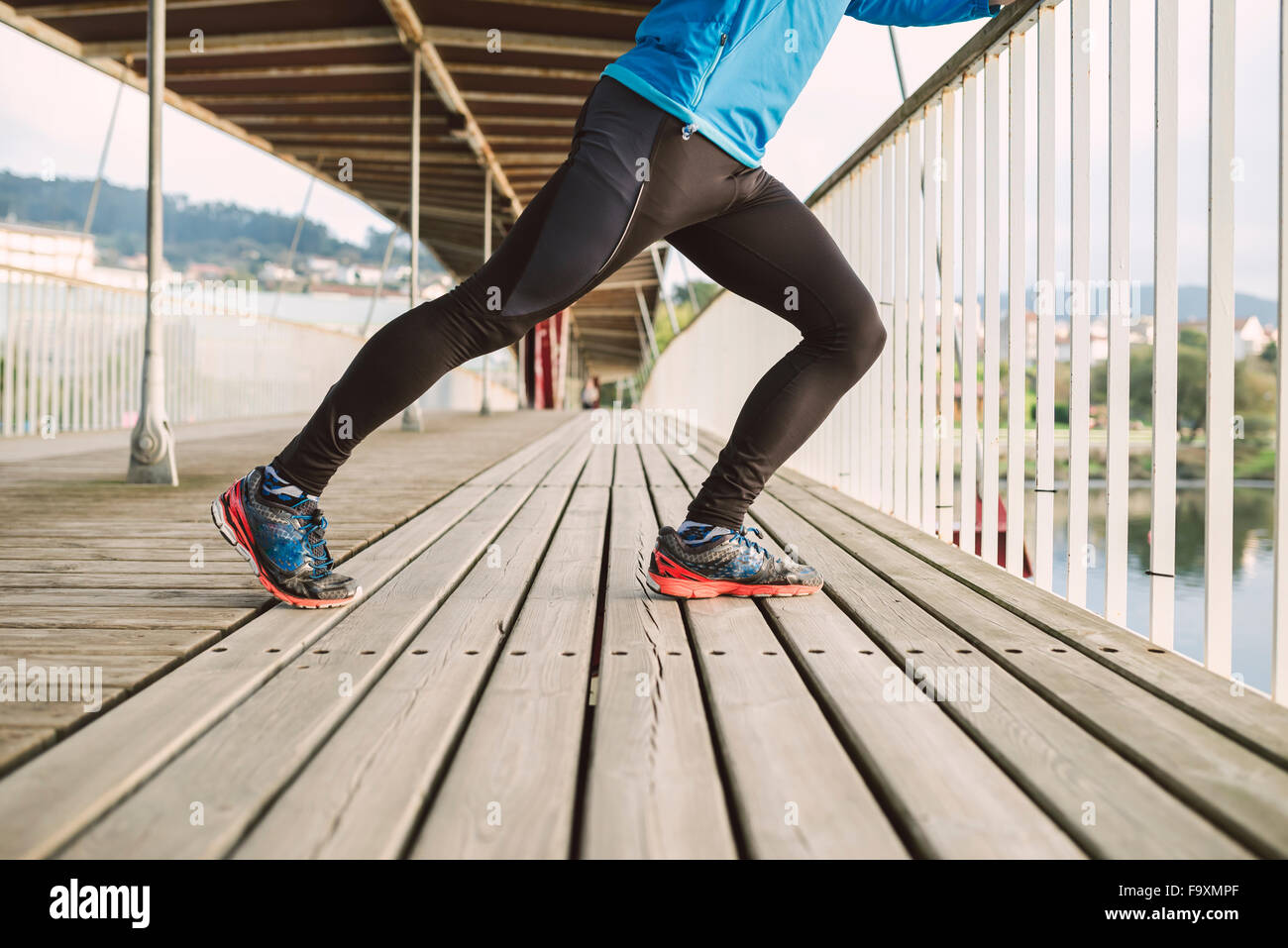 Spain, Naron, legs of a jogger stretching on a wooden bridge Stock ...