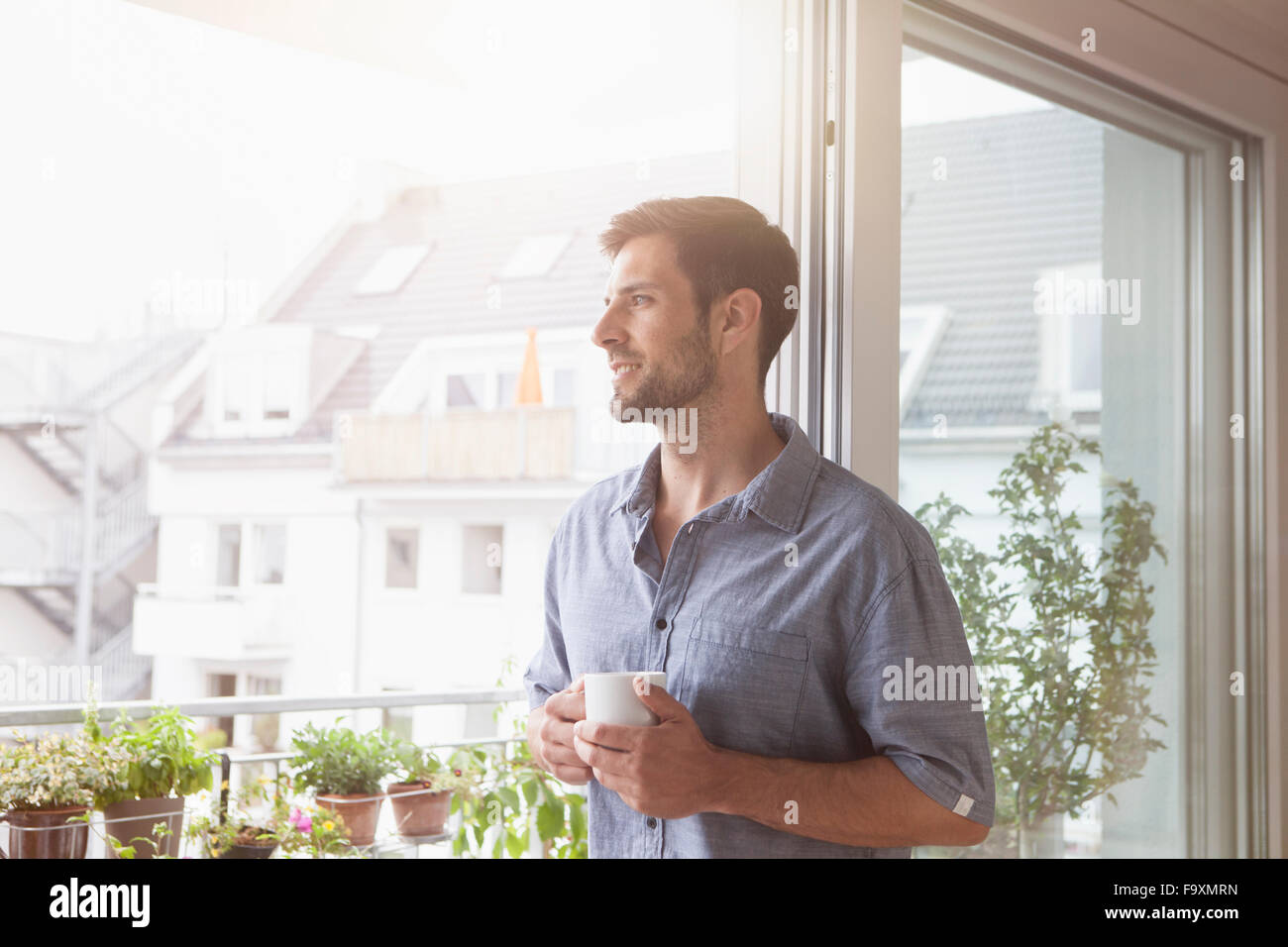 Smiling man looking out of window Stock Photo - Alamy