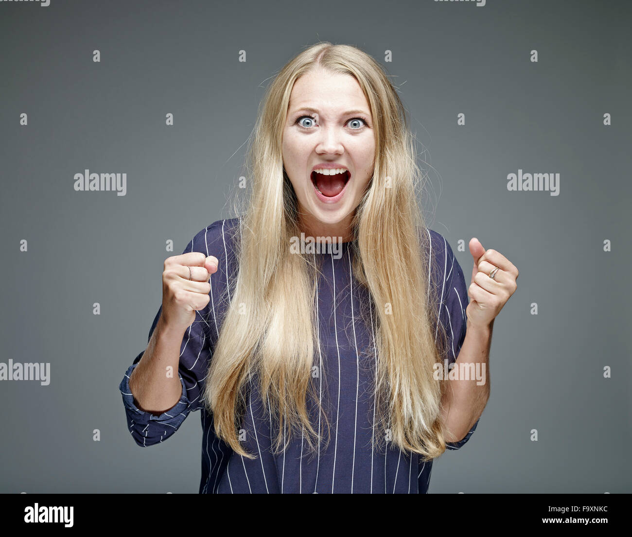 Portrait of excited young woman in front of grey background Stock Photo ...