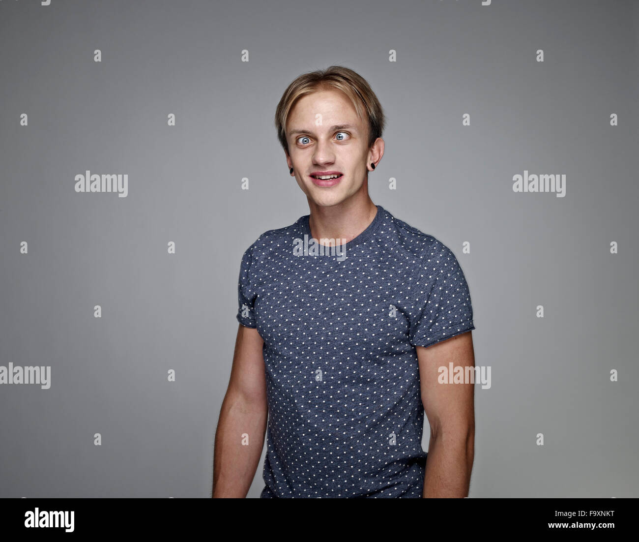 Portrait of cross-eyed young man in front of grey background Stock ...