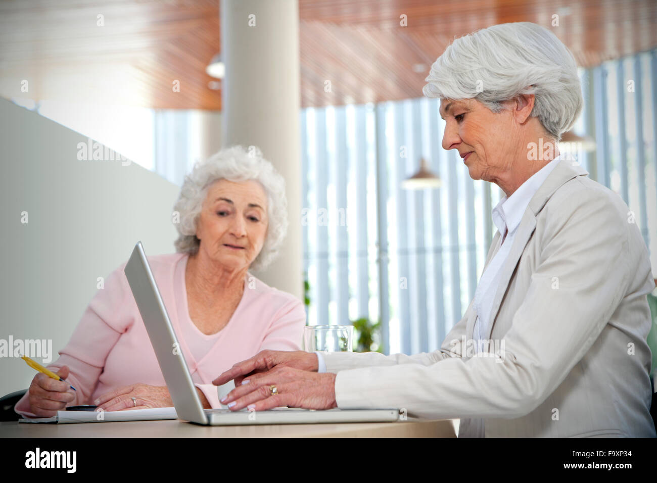 Two senior women working together at laptop Stock Photo - Alamy