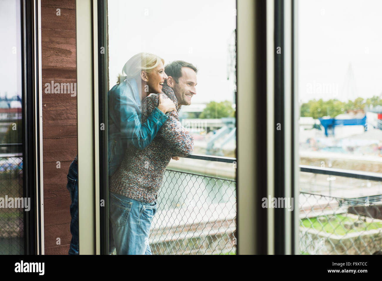 Happy couple standing together on balcony looking at distance Stock ...