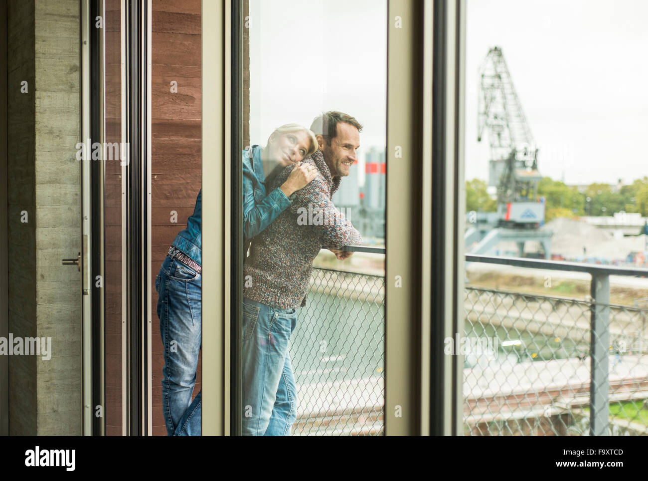 Happy couple standing together on balcony looking at distance Stock ...