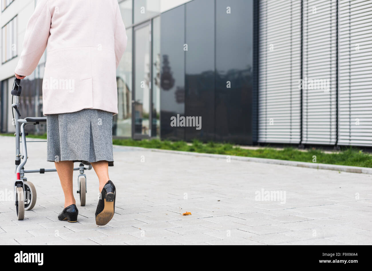 Senior woman walking with wheeled walker on pavement Stock Photo - Alamy