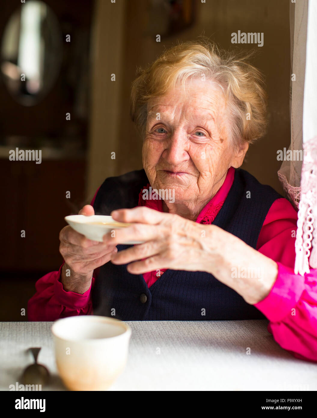 Happy old woman drinking tea in the kitchen Stock Photo - Alamy