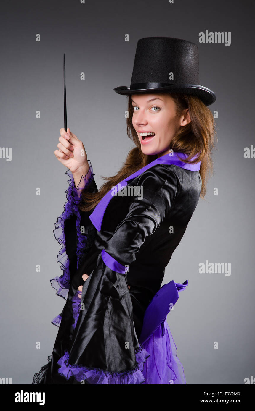 Pretty magician girl holding stick against gray Stock Photo - Alamy