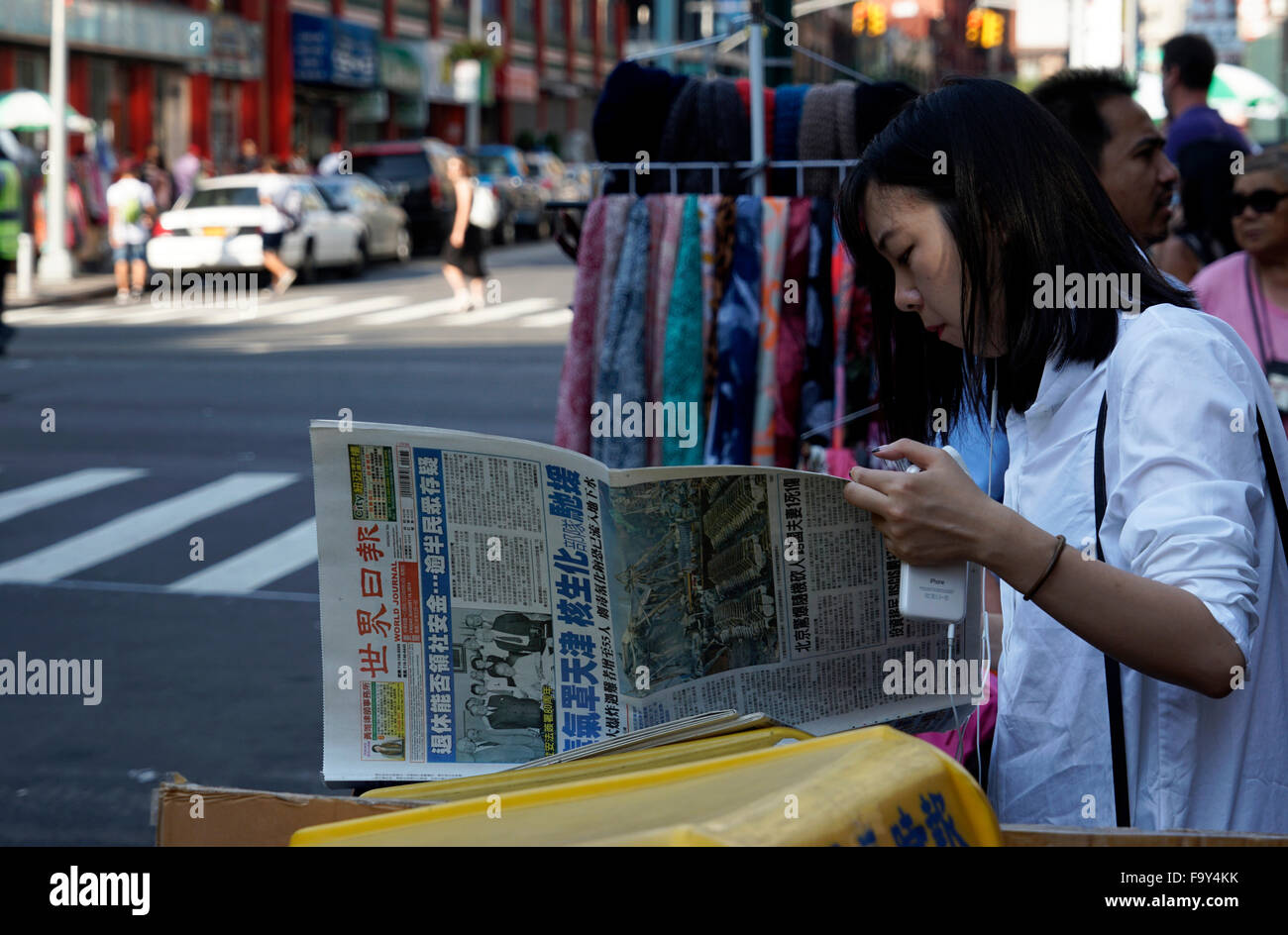 A woman reading Chinese newspaper on street corner in New York City ...