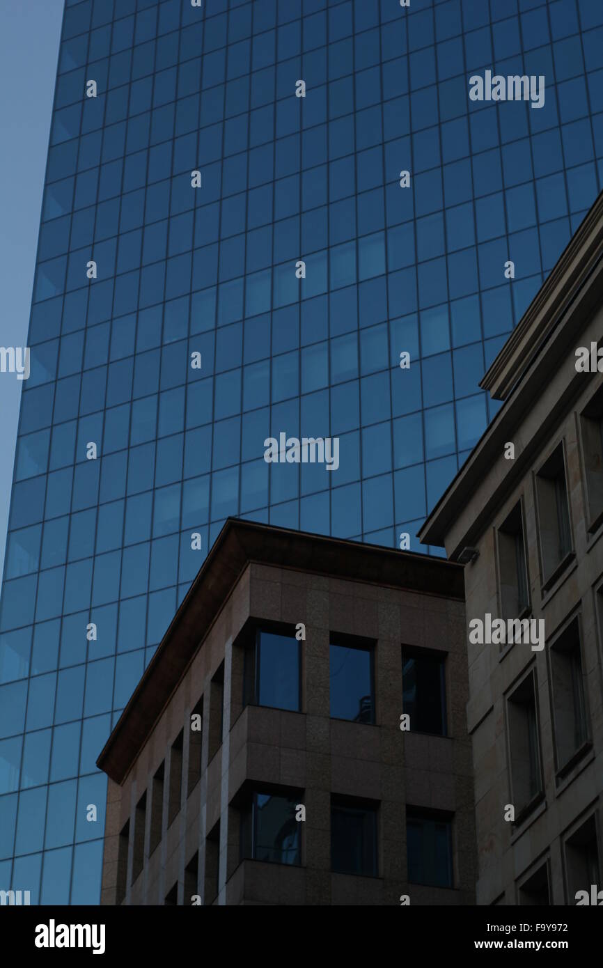 Modern glass faced skyscraper with concrete buildings close up Stock ...