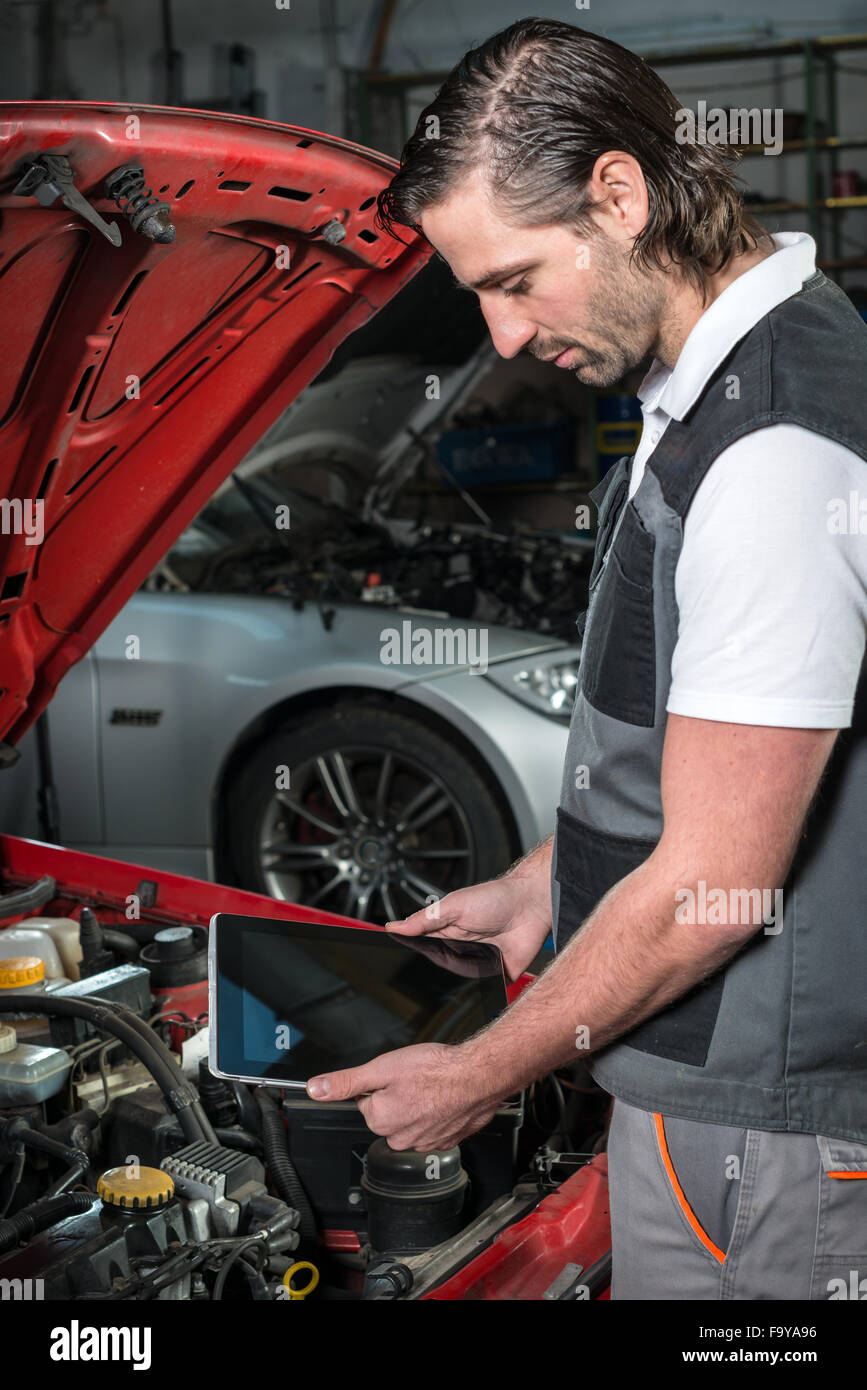 Mechanic using a tablet pc at the repair garage Stock Photo - Alamy