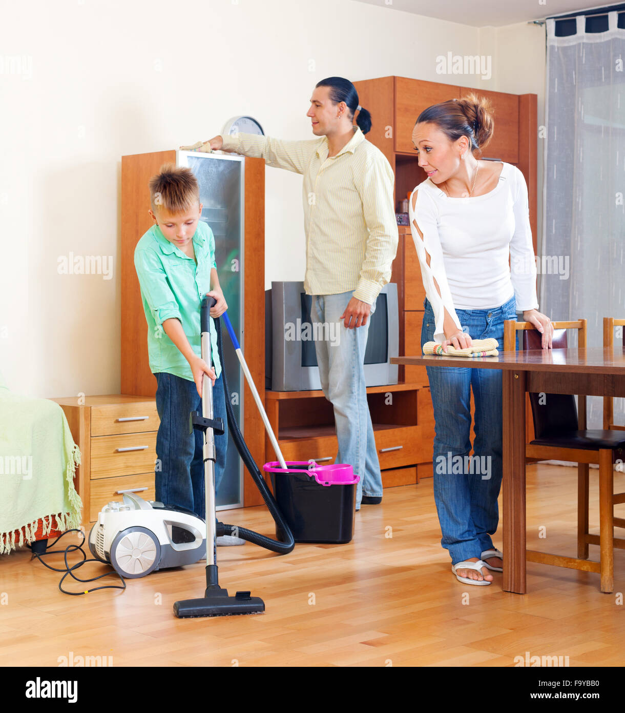 Parents and boy cleaning together in living room Stock Photo - Alamy