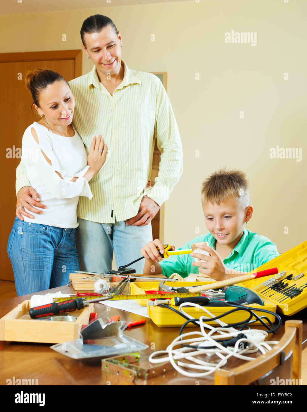 boy doing something with working tools, parents are watching in home ...