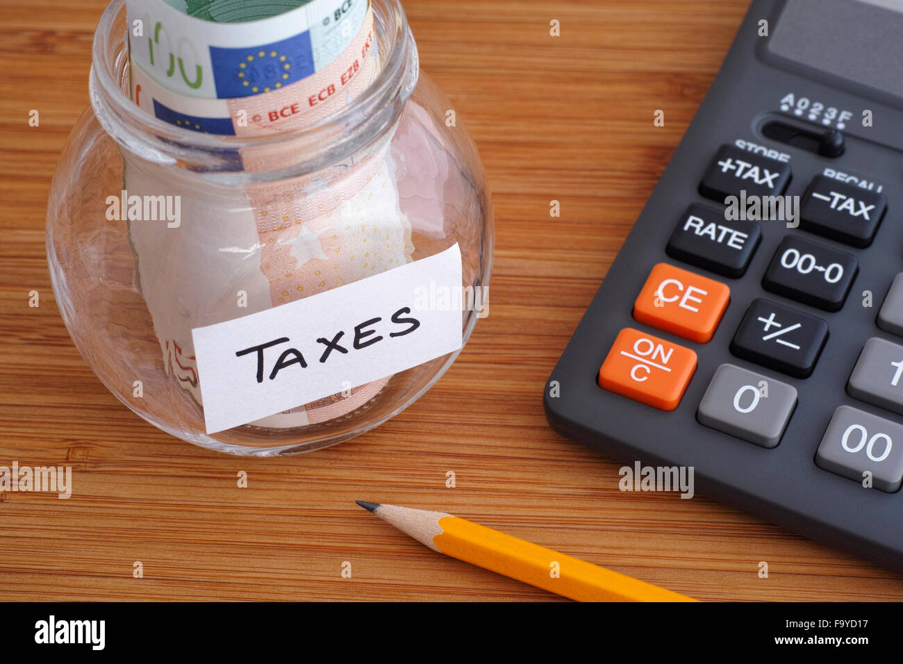 Euro banknotes in a glass jar with label Taxes. There are also ...