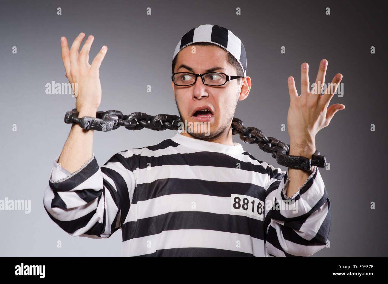 Young prisoner in chains against gray Stock Photo - Alamy